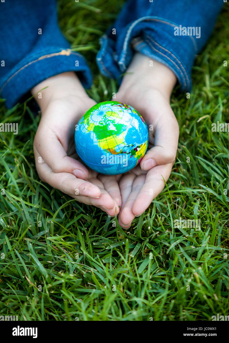 Young girl holding Earth in hands against green grass Stock Photo - Alamy