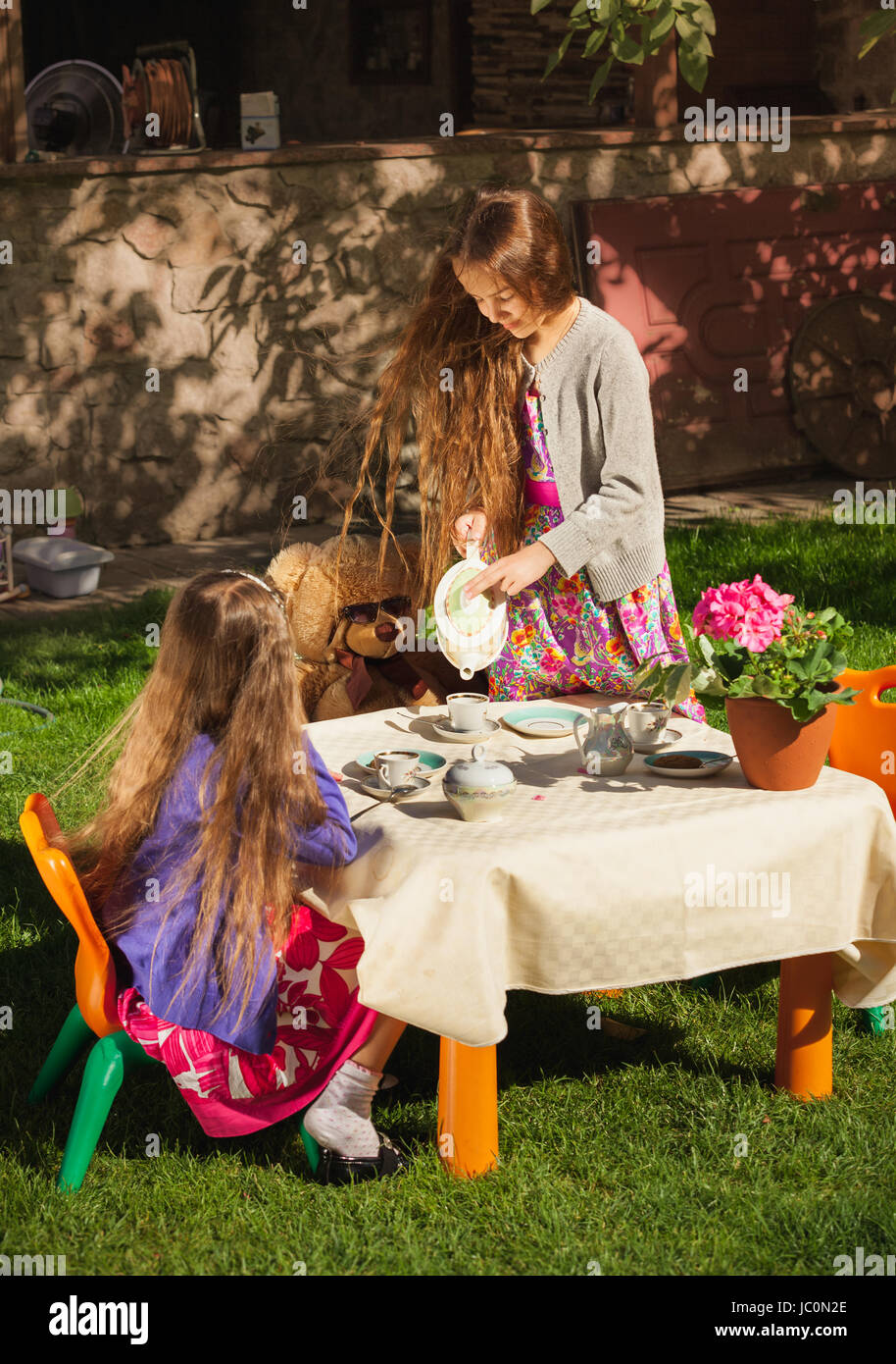 Beautiful girl pouring tea to her sister at toy tea party Stock Photo ...