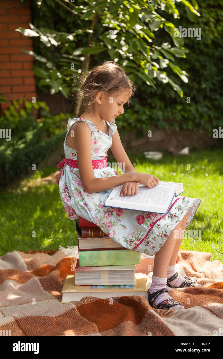 Cute smart girl reading big book at park at sunny day Stock Photo - Alamy