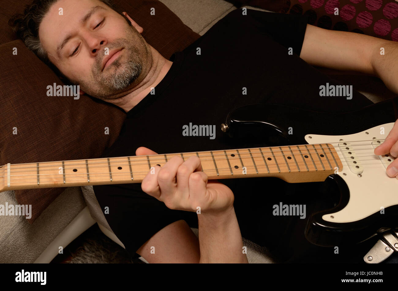 Man playing guitar on a couch Stock Photo - Alamy