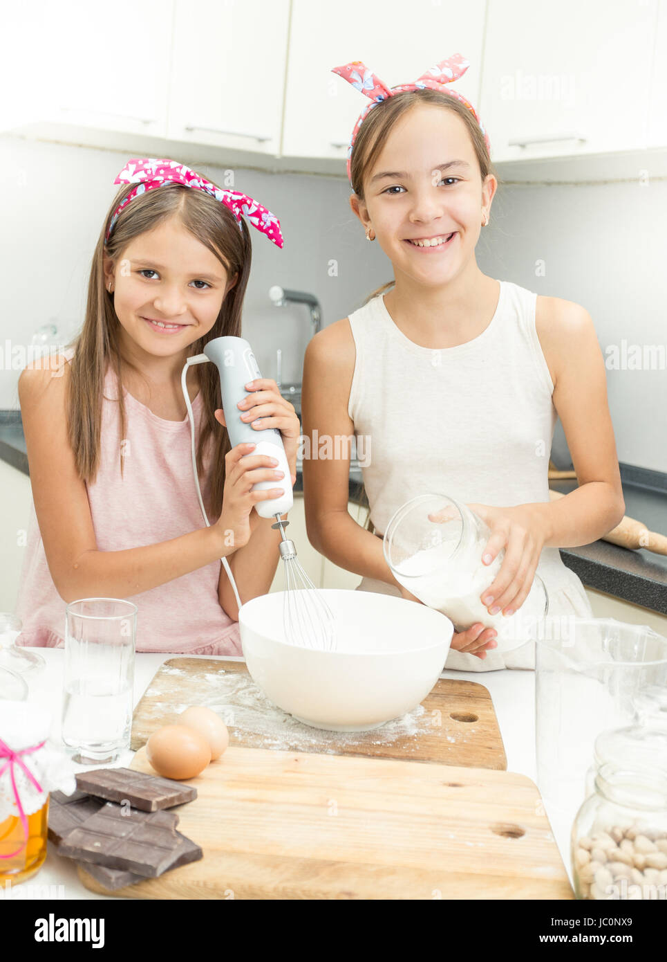 Portrait of two smiling girls cooking pie and making dough Stock Photo ...