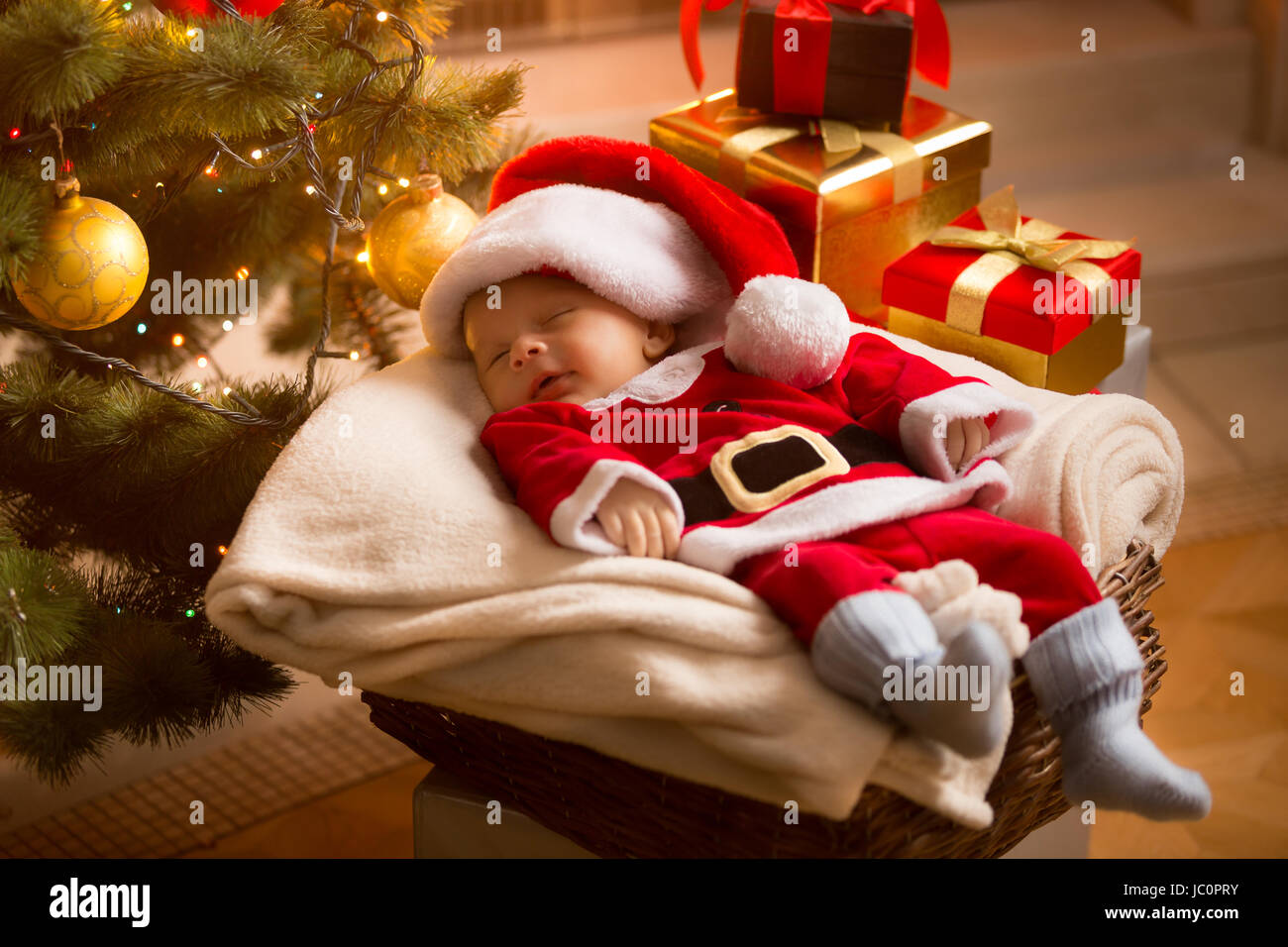 Little baby Santa sleeping under Christmas tree with presents Stock ...