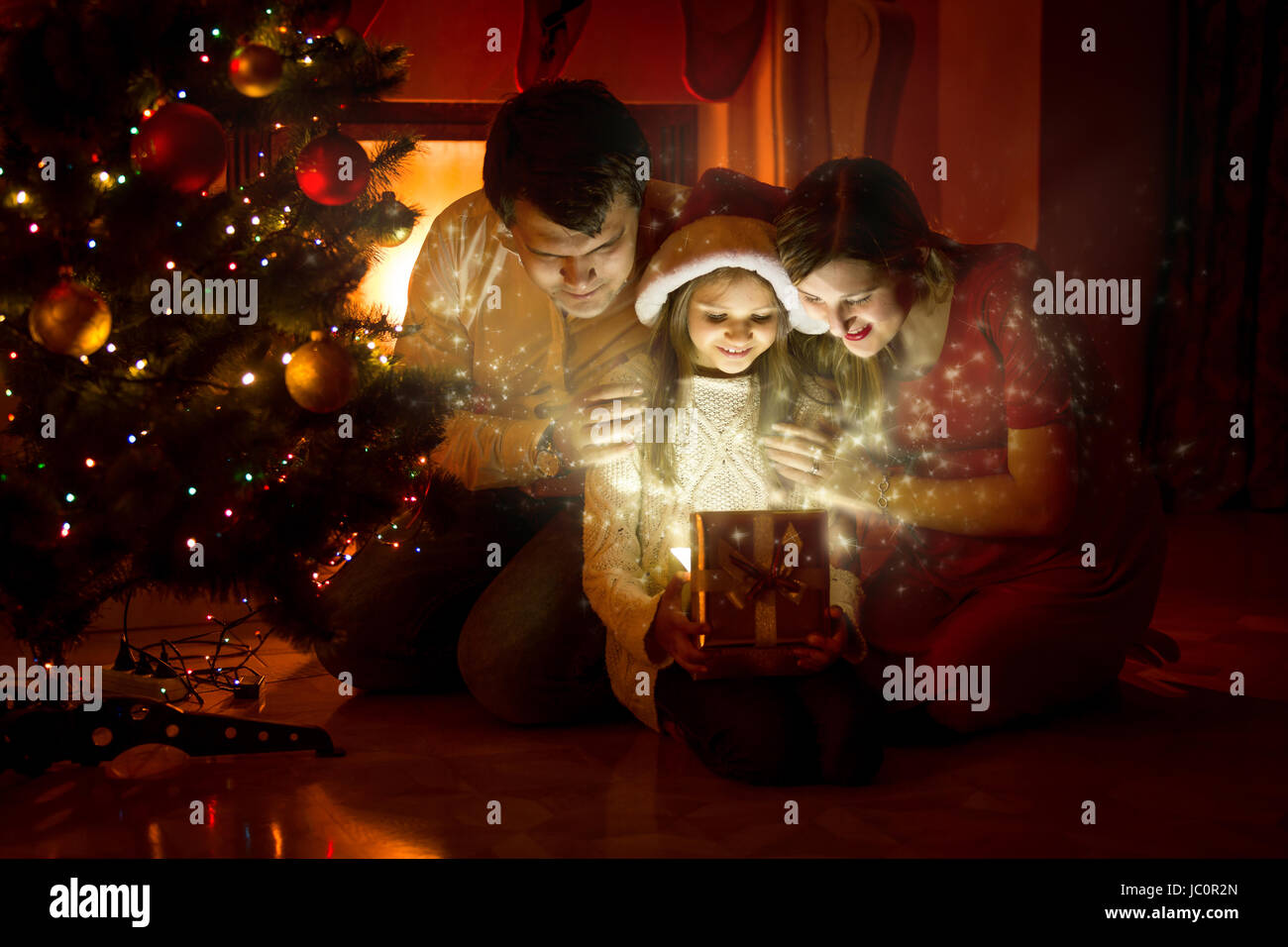 Happy family looking inside of magic Christmas gift box Stock Photo - Alamy