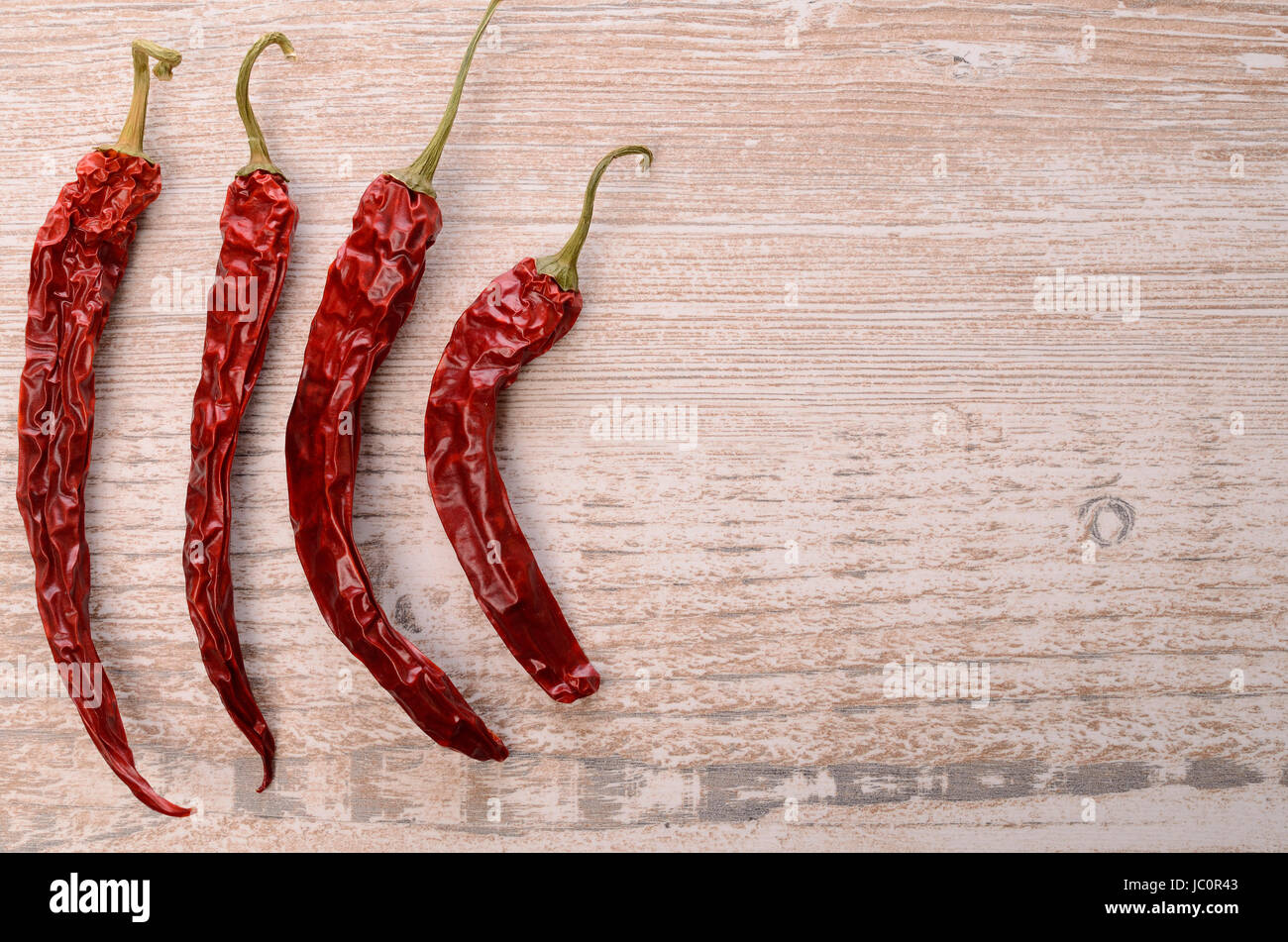 Four dried chilies on a rustic wooden background with space for text ...