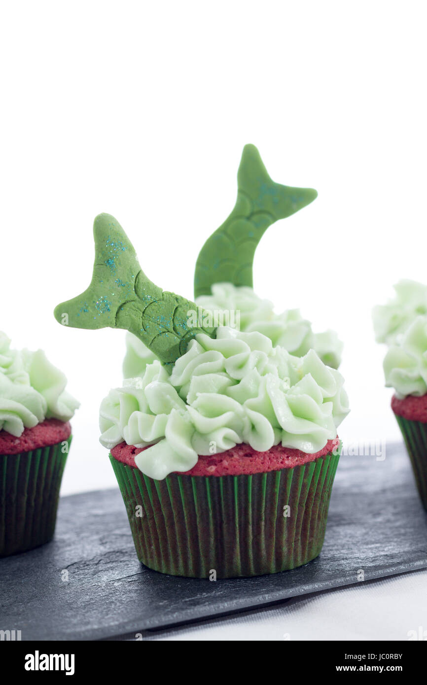 Tasty cupcakes with green icing and fish tails decoration on a shale ...