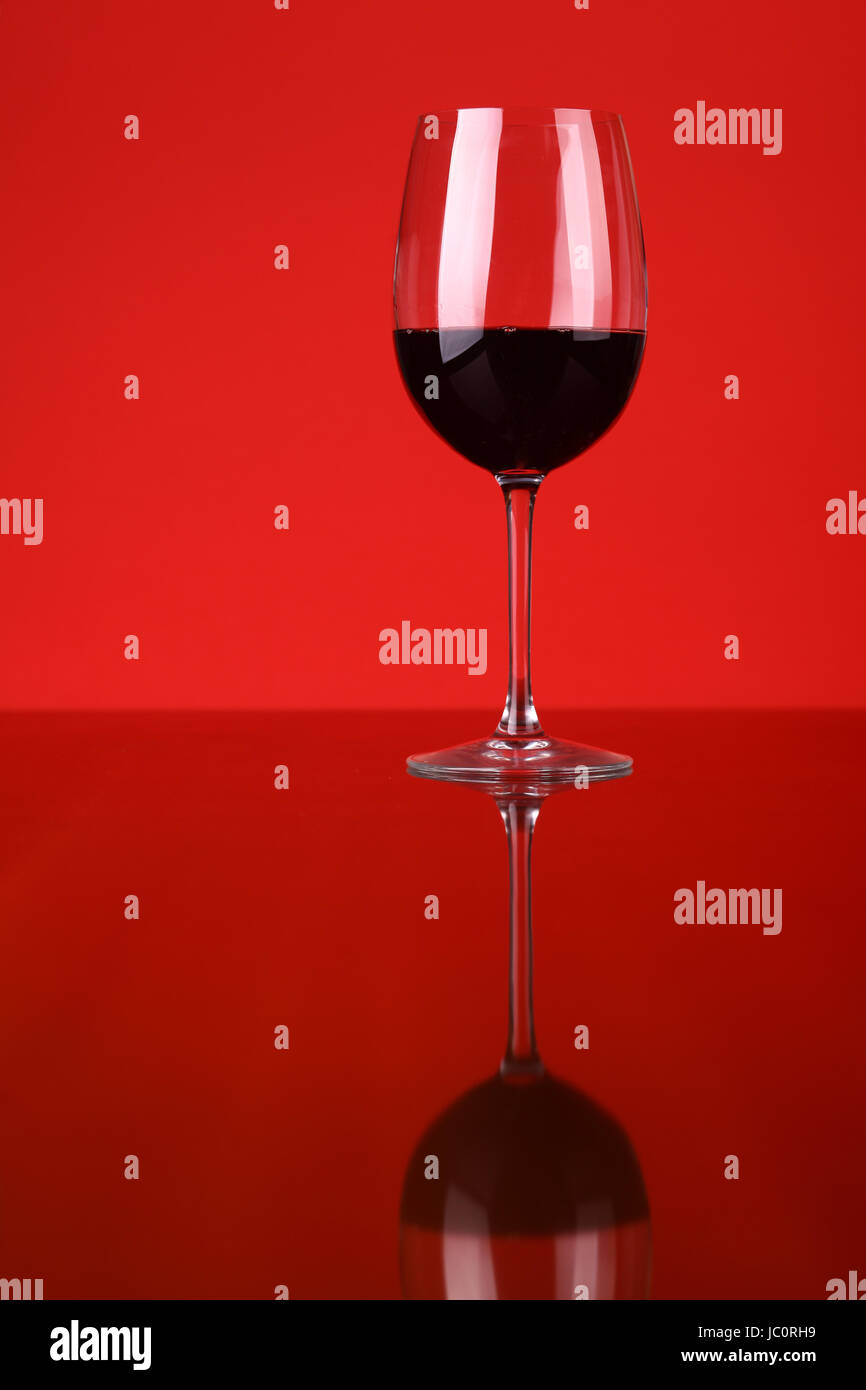 Glass of red wine over a red background Stock Photo - Alamy