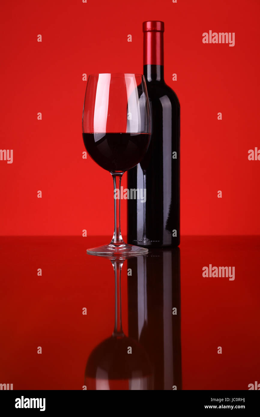 Glass and bottle of red wine over a red background Stock Photo - Alamy