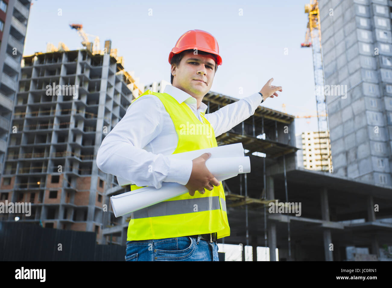 Closeup portrait of architect in hardhat showing building under ...
