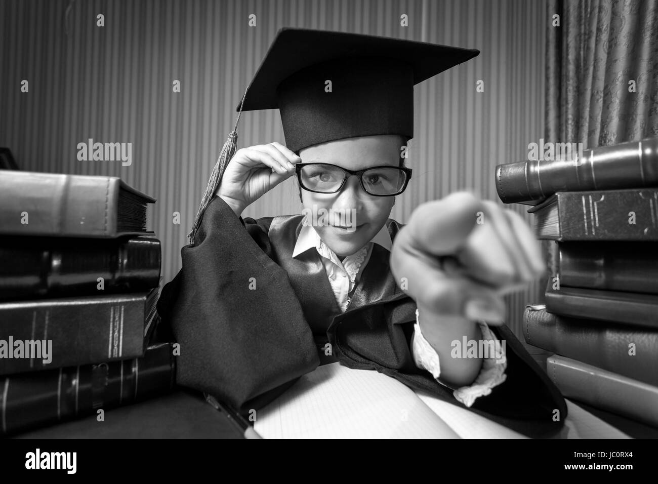 Black and white portrait of girl in graduation cap and gown pointing at ...