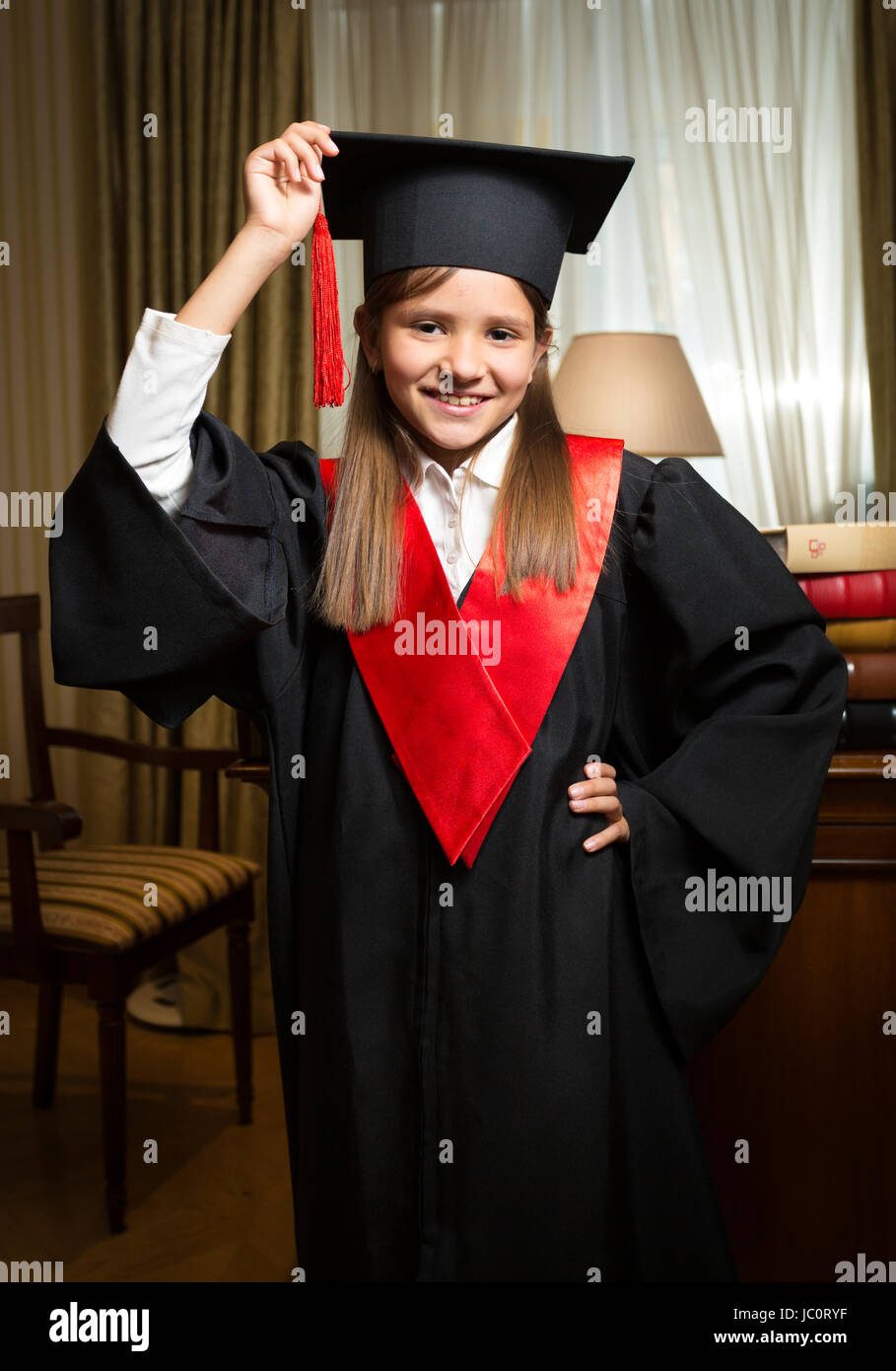 Portrait of happy smiling girl in graduation cap and gown posing at ...