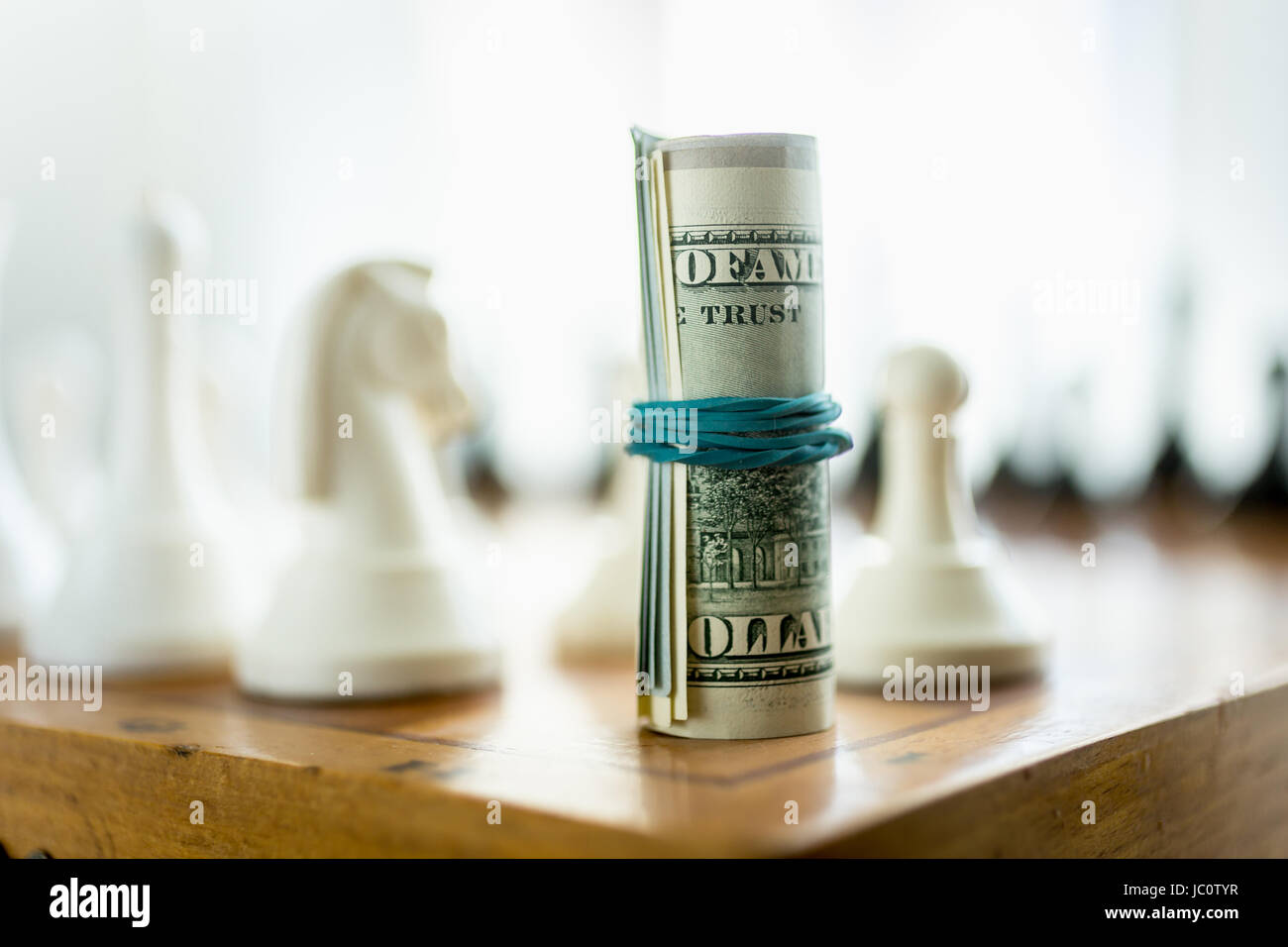 Twisted dollar bills standing on chess board in place of tower piece ...