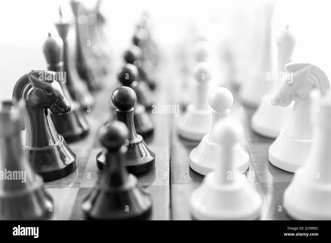 Black and white closeup photo of chess pieces standing in rows face to ...