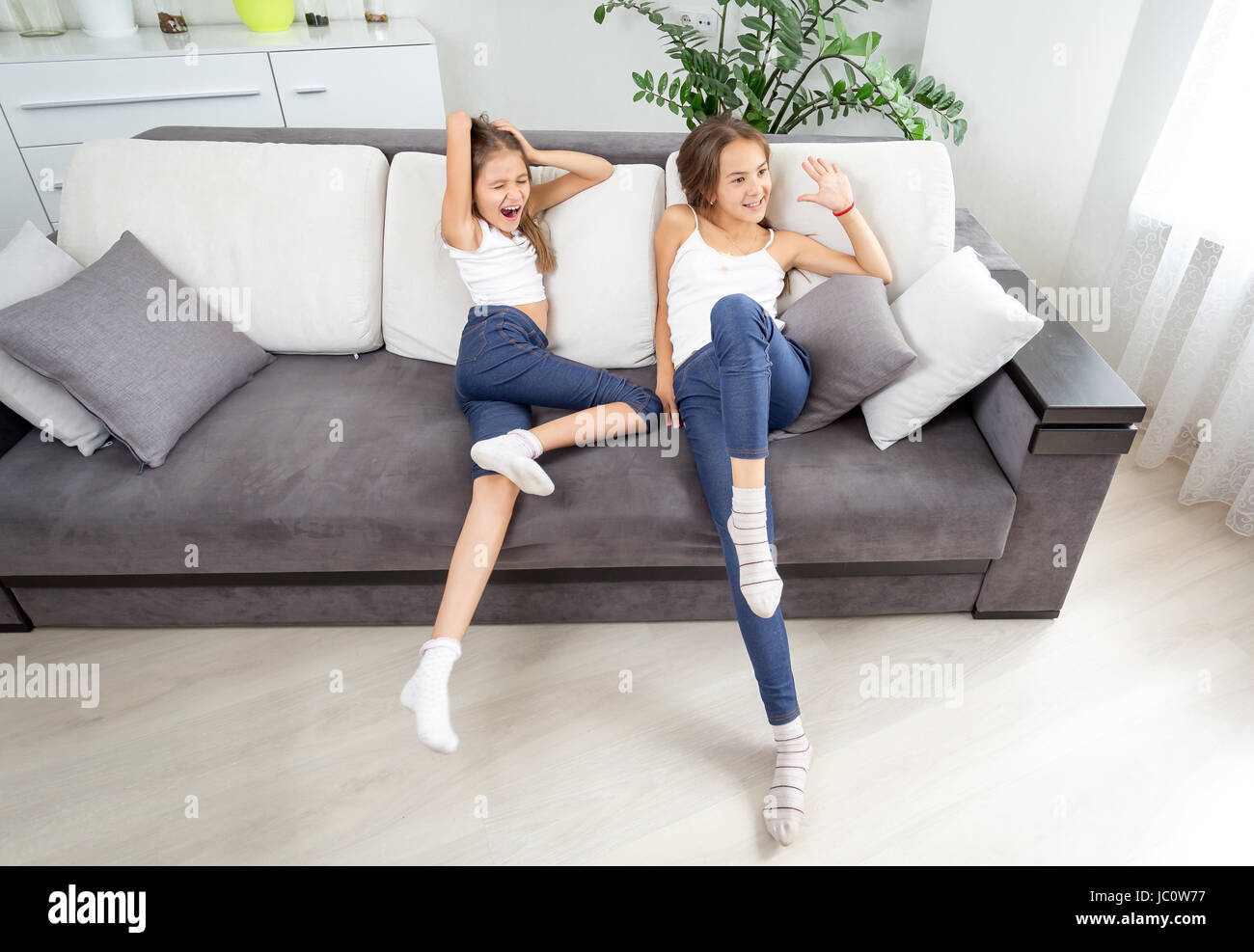 Two happy girls having fun on sofa at living room Stock Photo - Alamy