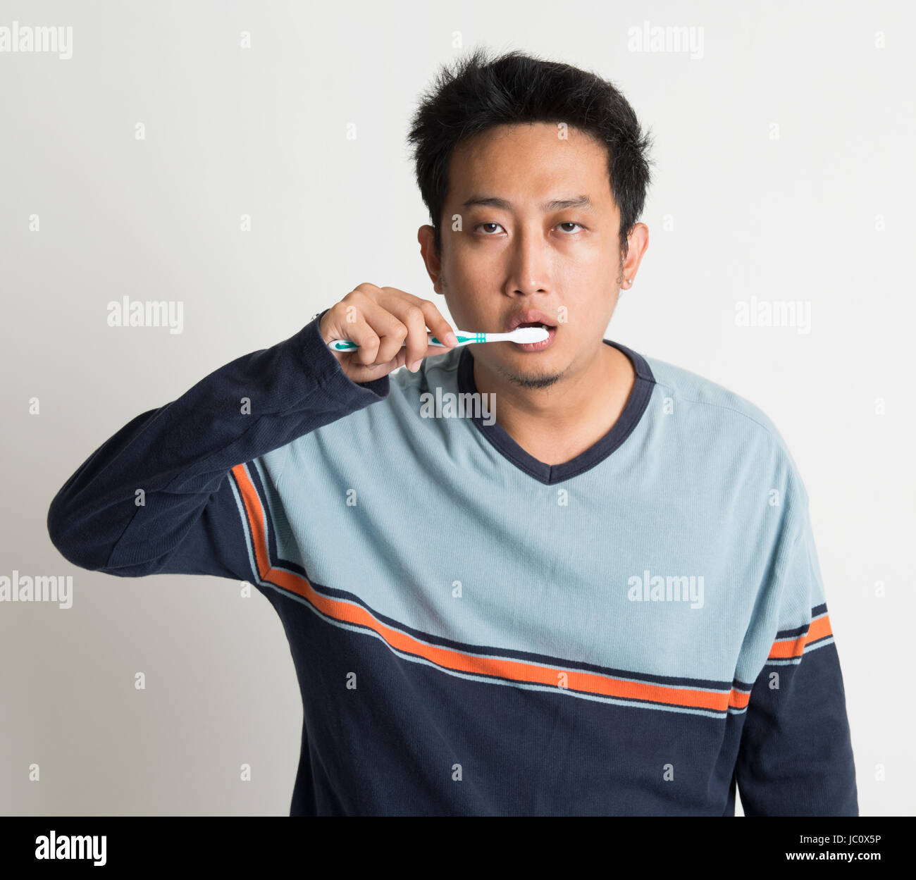 Southeast Asian male brushing teeth with sleepy eyes in a morning, on ...