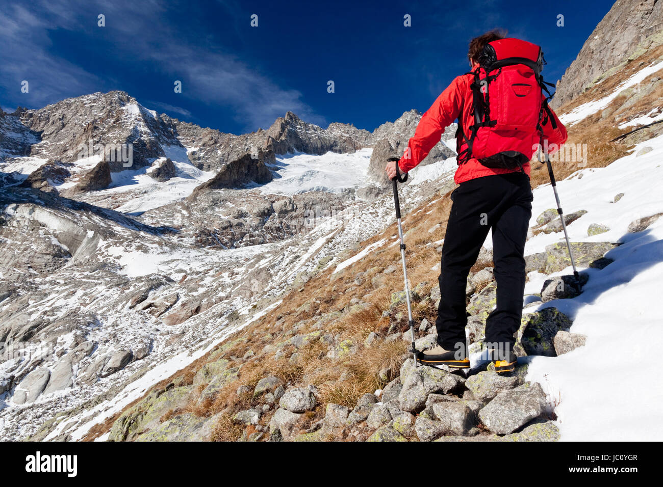 Back view of a young male hiker while observing a high mountain ...