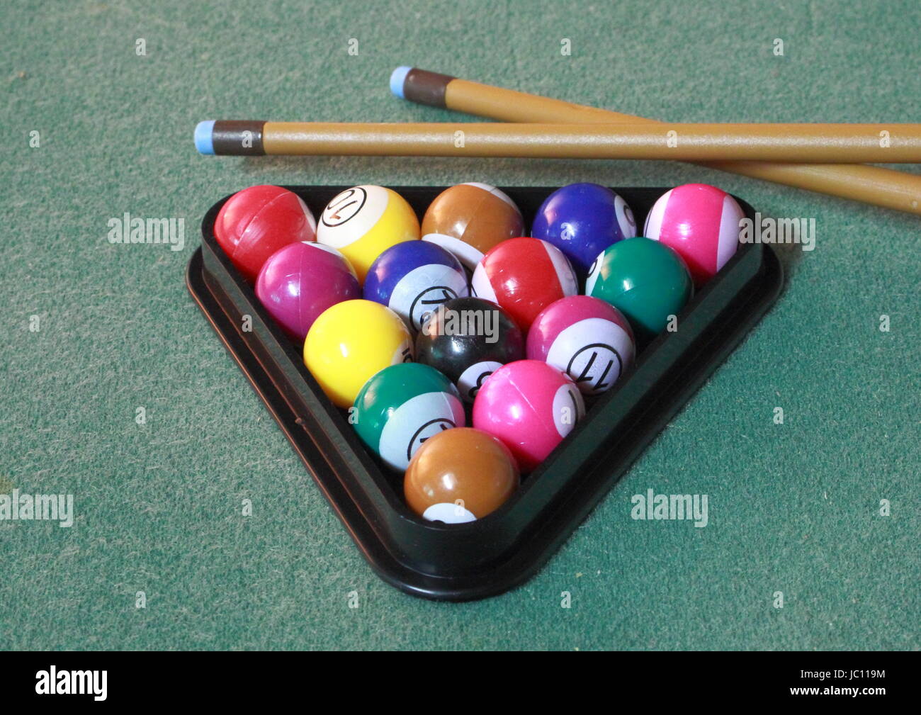 Pool balls on green cloth in triangle with cues Stock Photo - Alamy