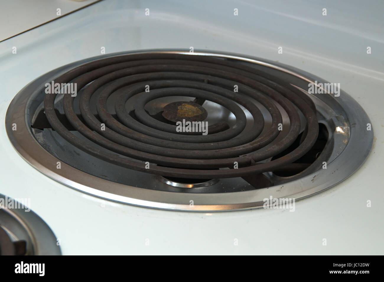 A coiled electric heating element on a modern stove, rusted with chrome ...
