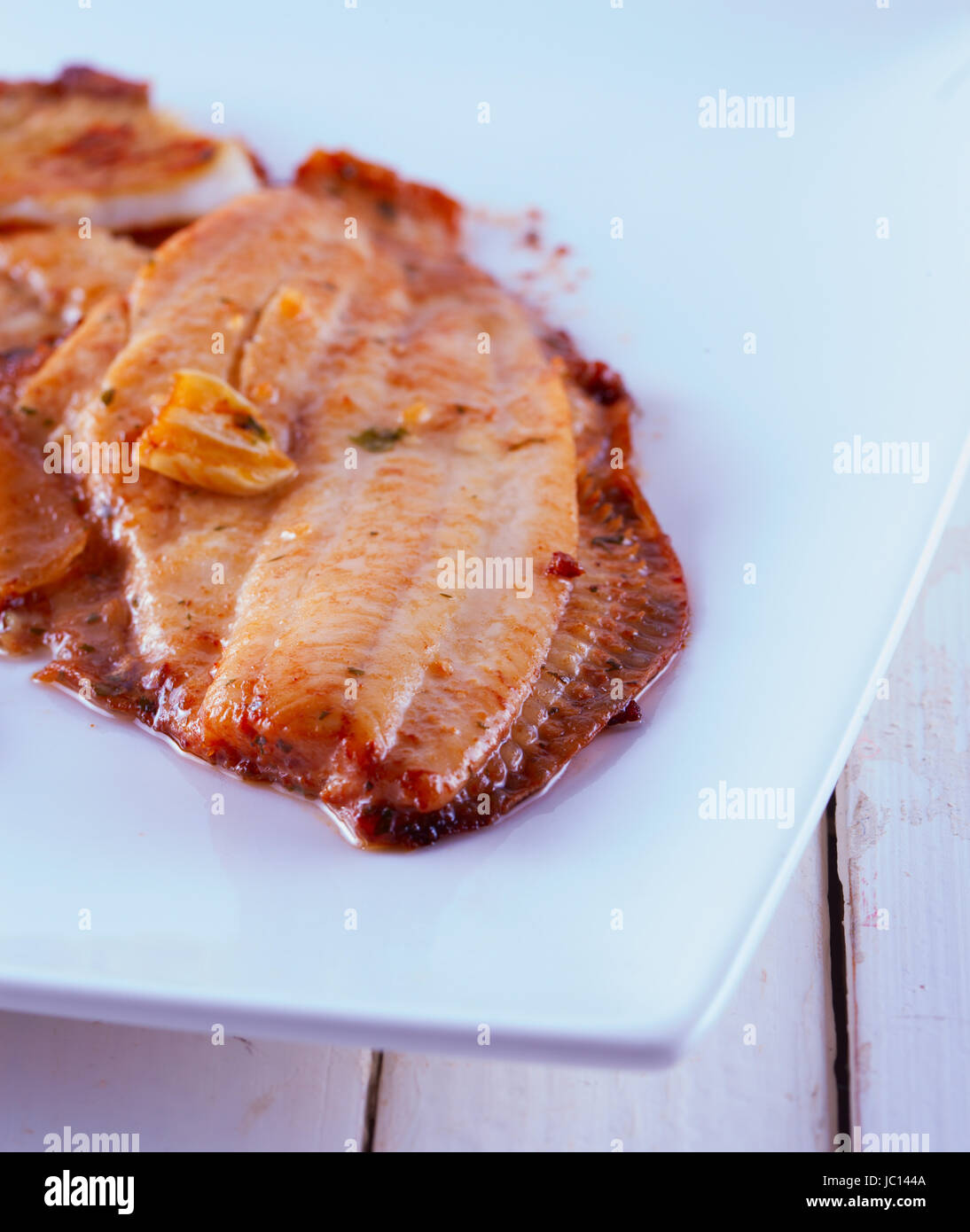 Baked hake over a white plate, with garlic Stock Photo - Alamy