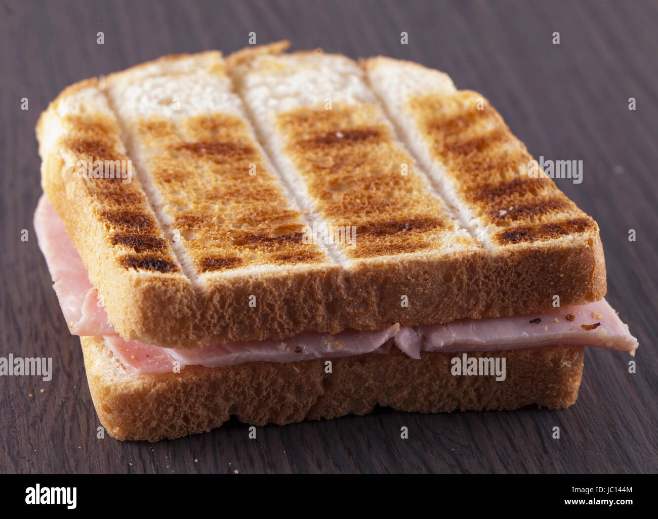 Toast with ham over dark wooden table Stock Photo - Alamy