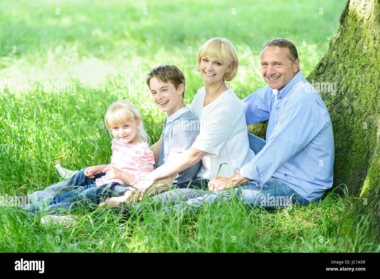 Jovial family resting under a tree in shade Stock Photo - Alamy
