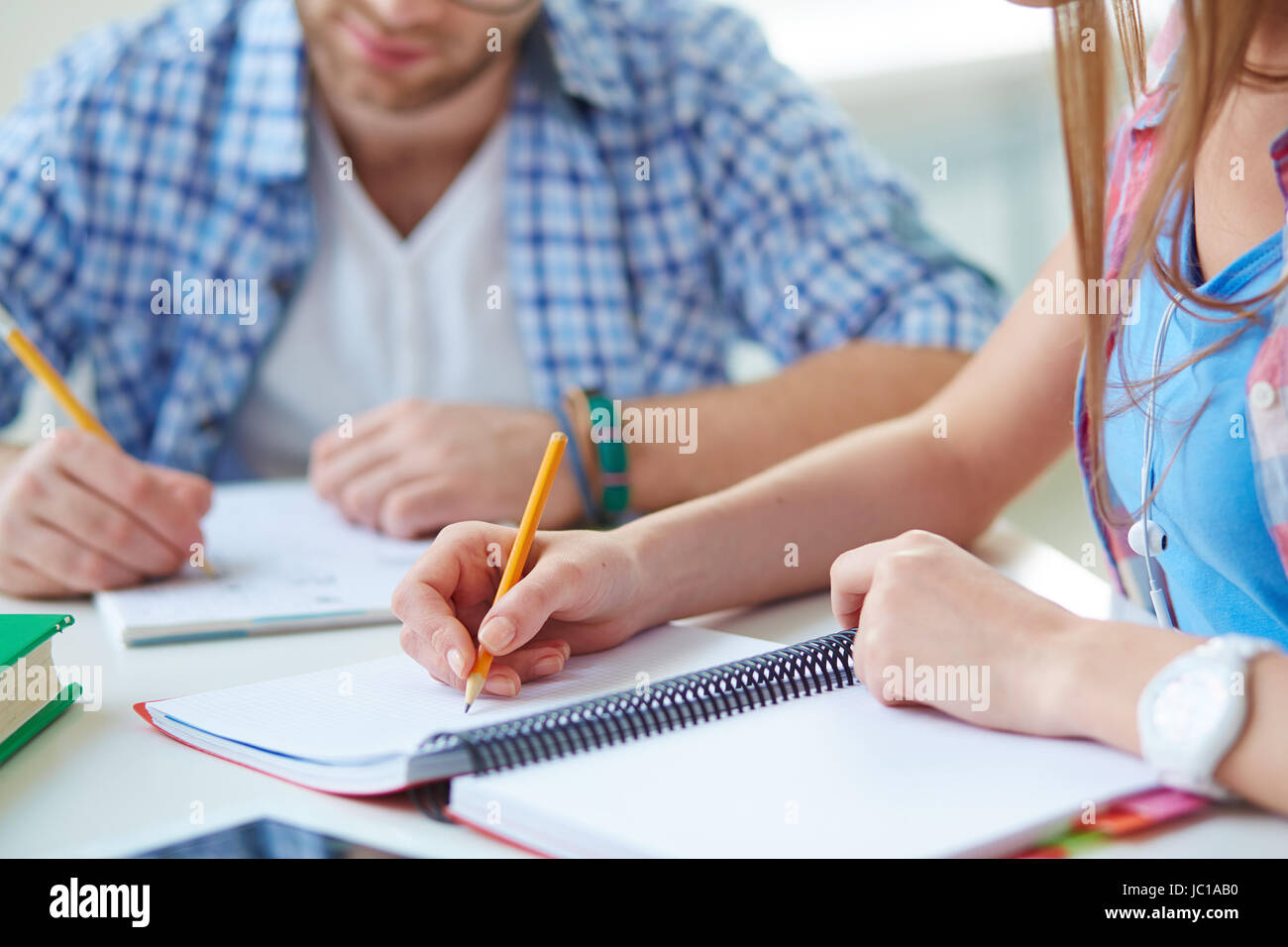 Hand of student with pencil making notes in exercise-book in working ...