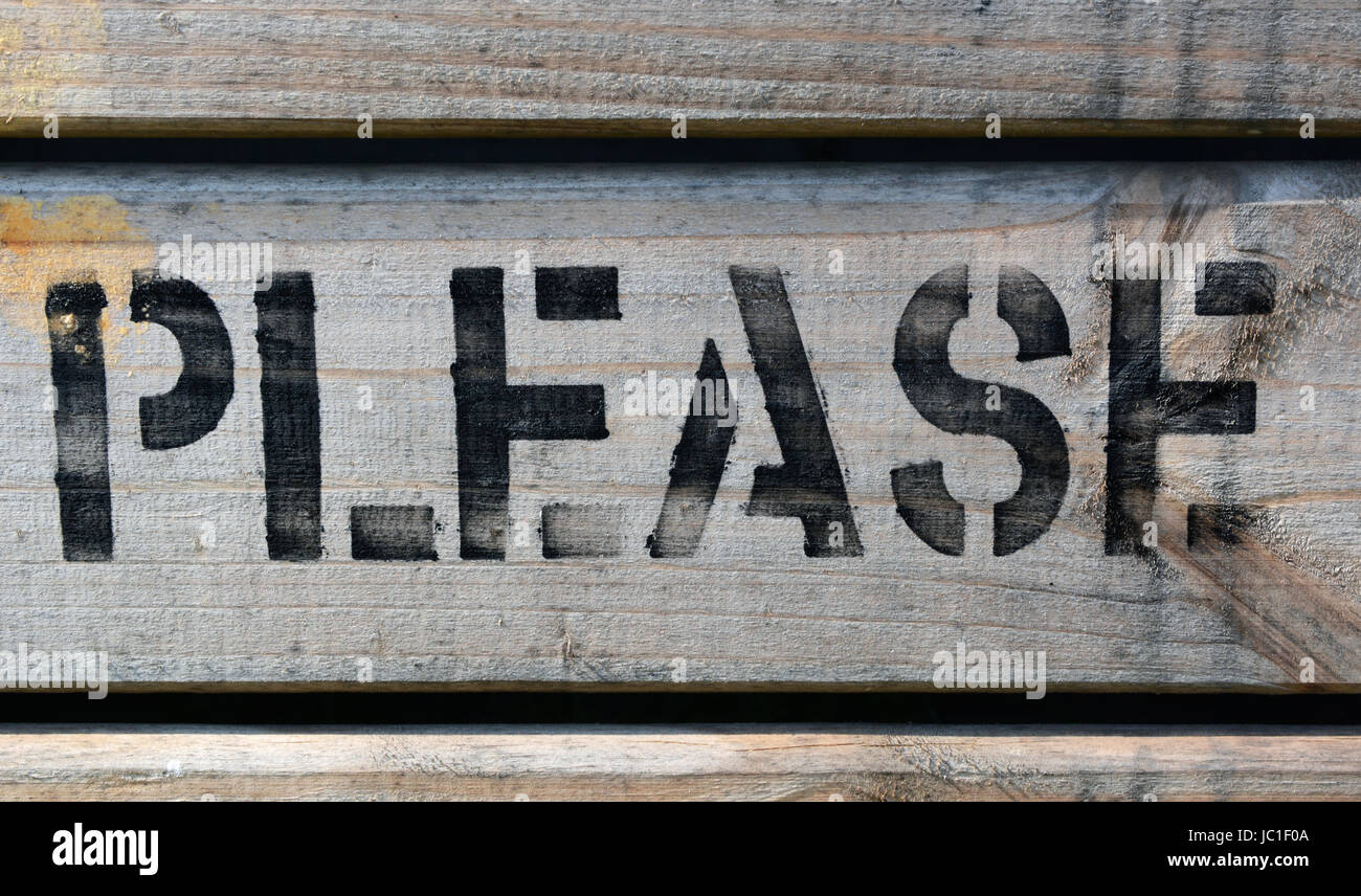 The word PLEASE stencilled in block capitals with black paint on wood ...
