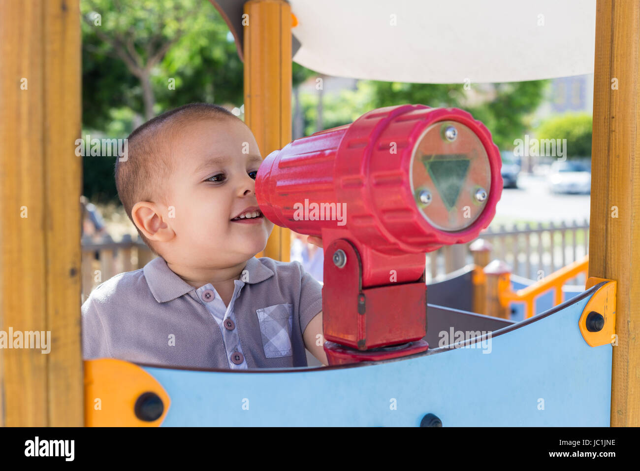 A toddler looking through a toy telescope in a playground Stock Photo ...