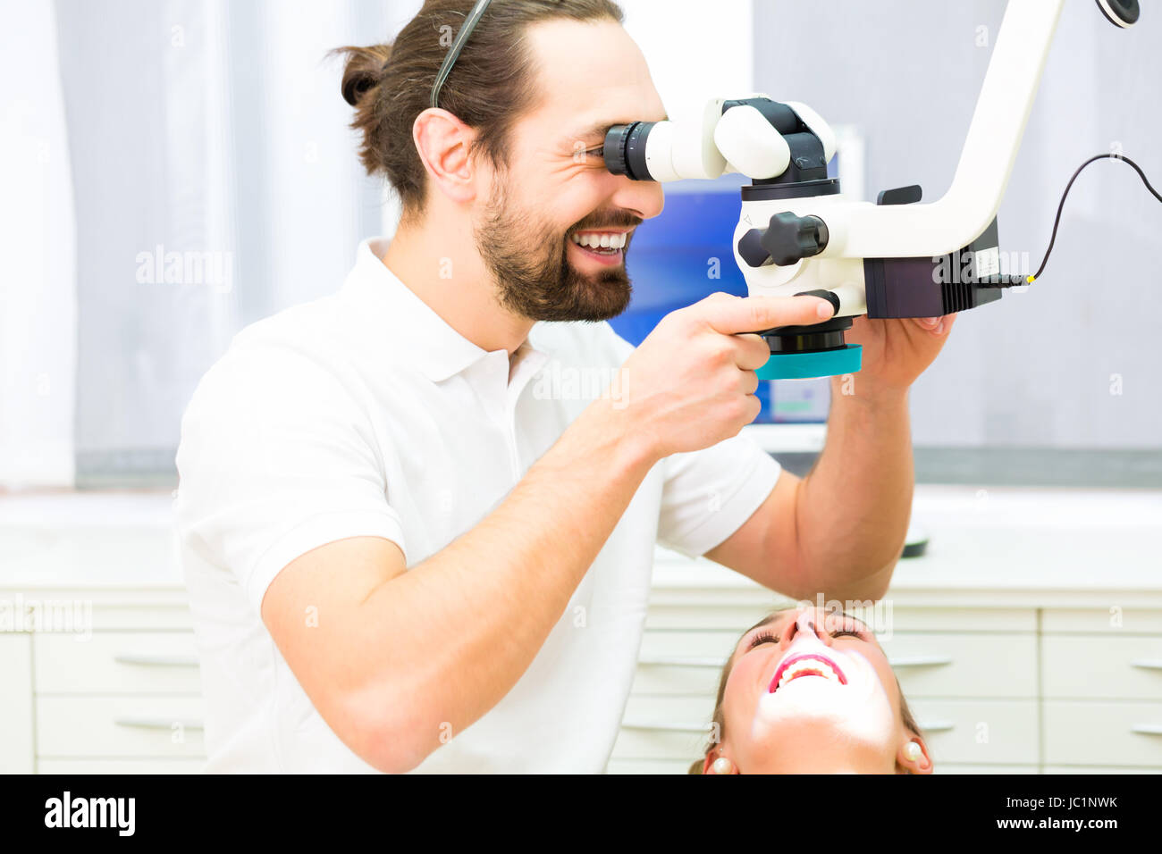 Dentist using microscope to check teeth of patient Stock Photo - Alamy