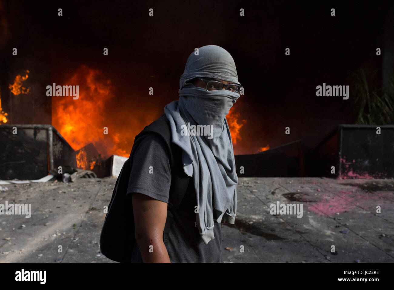Caracas, Venezuela. 12th June, 2017. A hooded protester stands in front ...