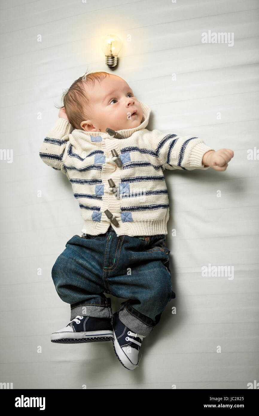 Portrait of cute baby boy posing on bed with glowing light bulb ...