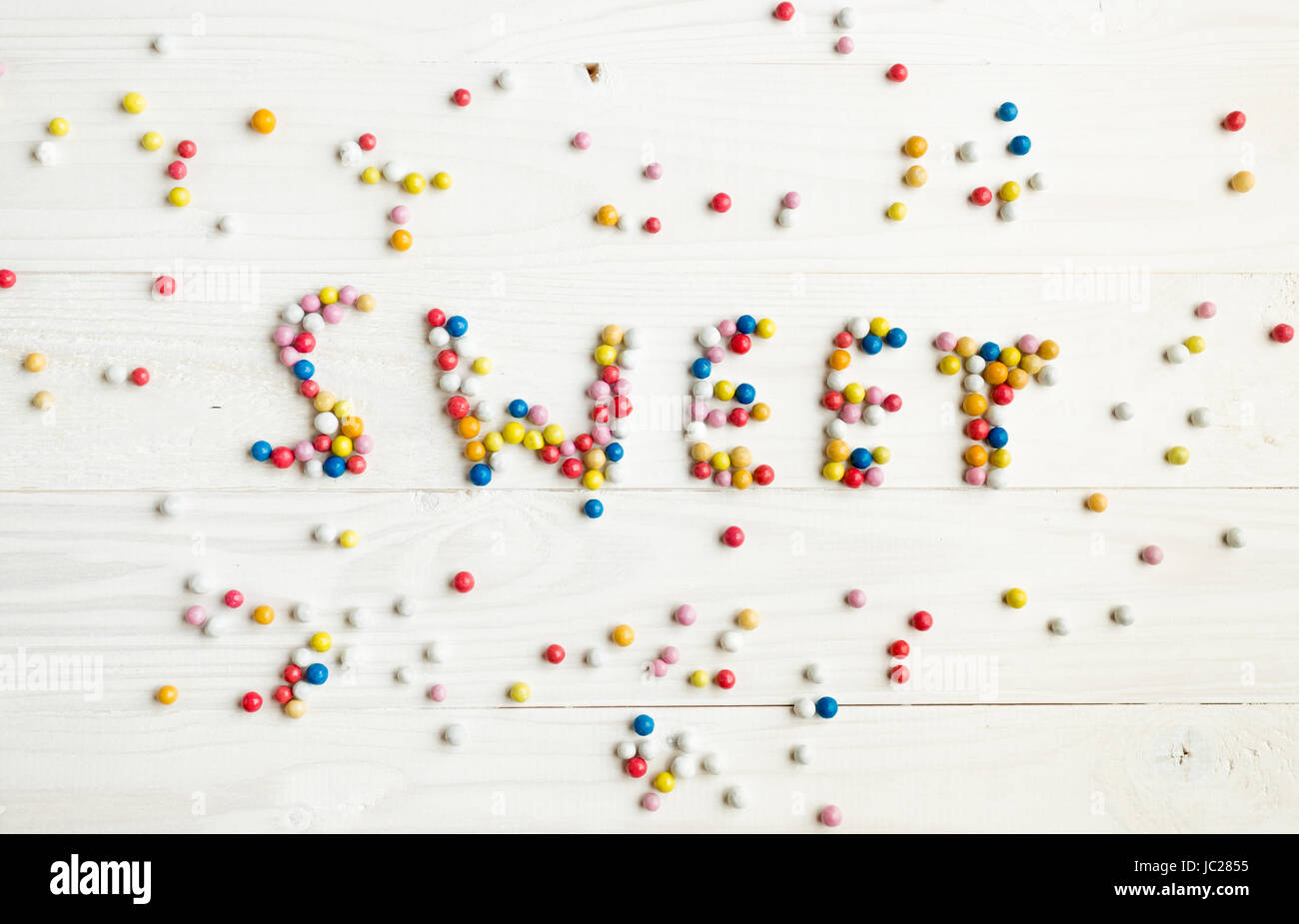 Word Sweet written by little colorful candies on white wooden ...