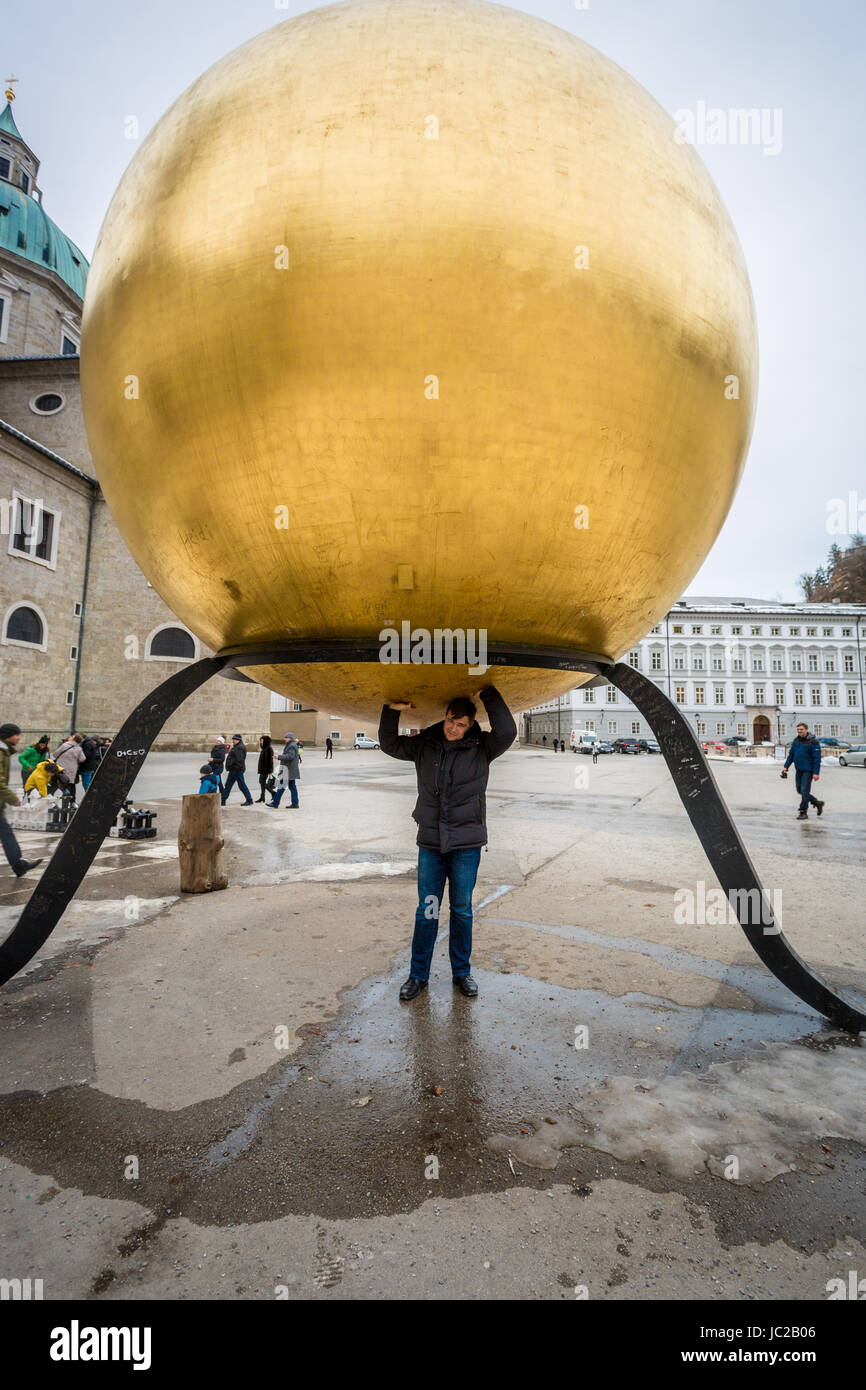 Outdoor shot of male tourist holding statue of big golden ball Stock ...