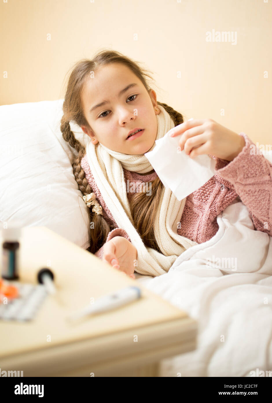 Portrait of sick girl lying in bed and holding paper tissue Stock Photo ...