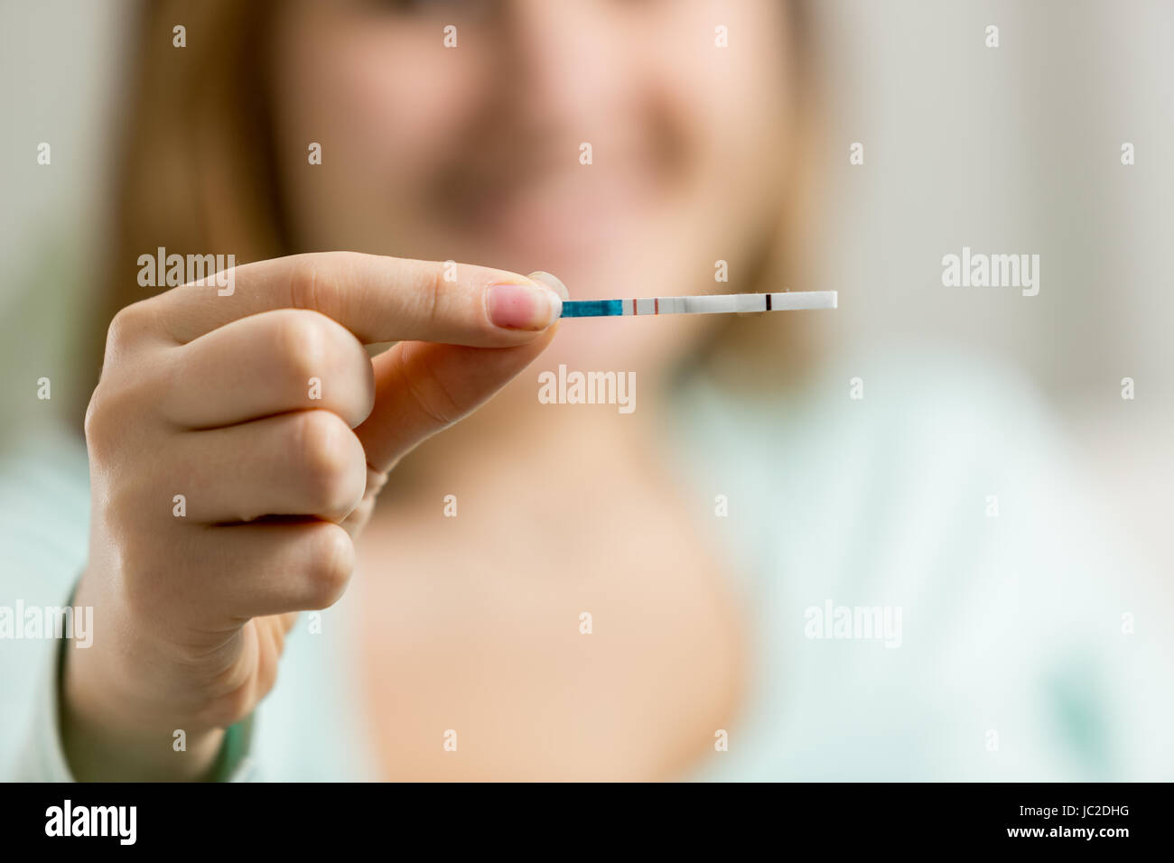 Happy woman holding pregnancy test with two lines Stock Photo - Alamy