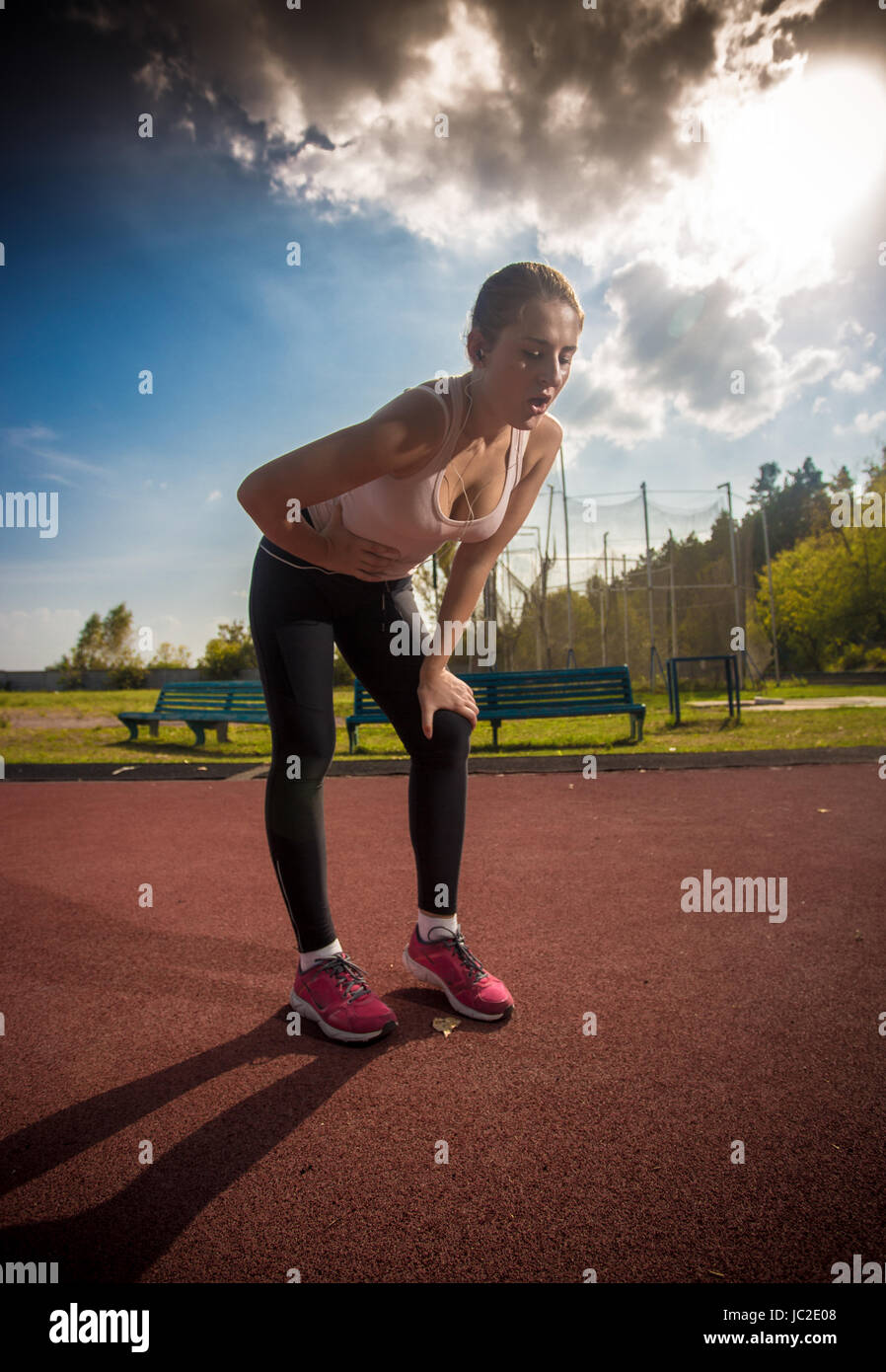 Tired woman resting after running on sport arena at hot sunny day Stock ...