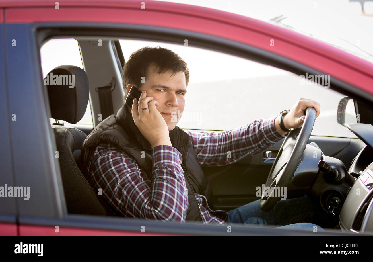 Closeup portrait of male driver talking by phone while driving a car ...