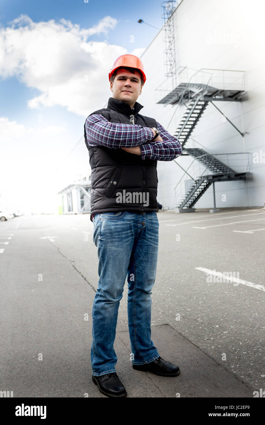 Handsome adult worker posing on road against big factory Stock Photo ...