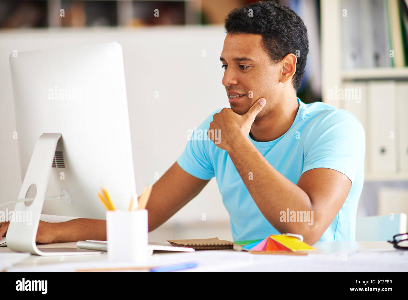 Smart guy sitting at workplace and working with computer Stock Photo ...
