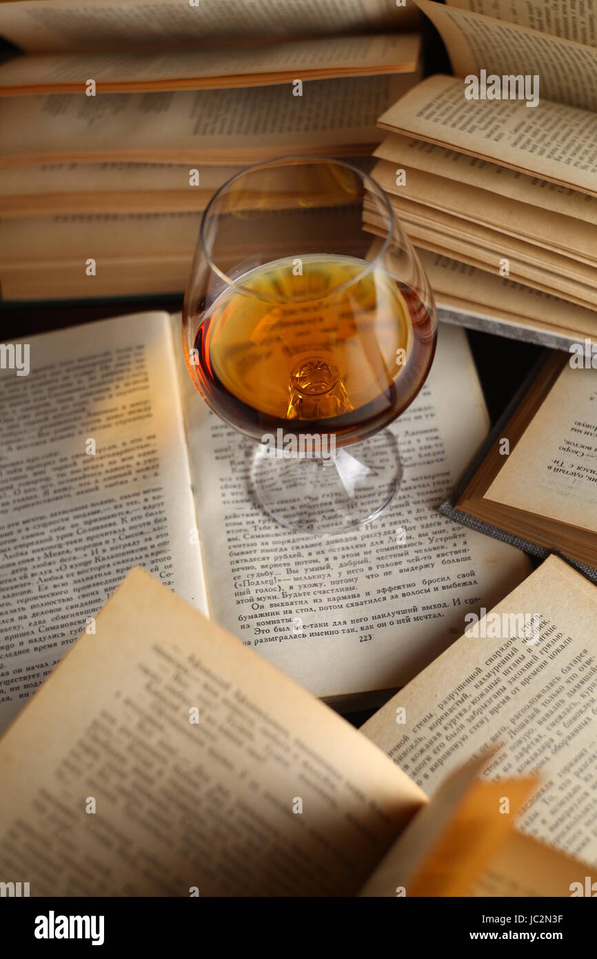 Glass of brandy standing on open books Stock Photo - Alamy