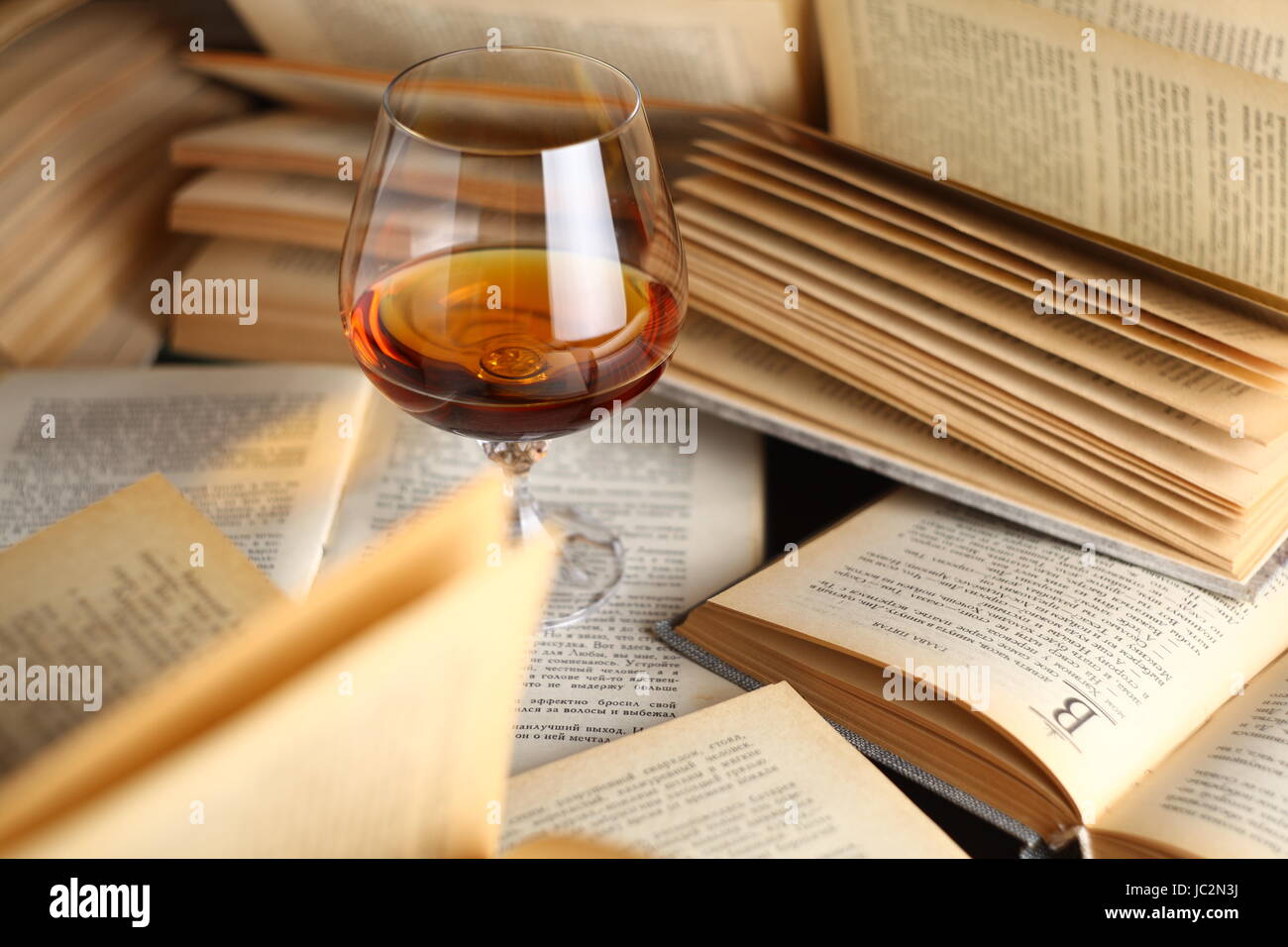 Glass of brandy standing on open books Stock Photo - Alamy