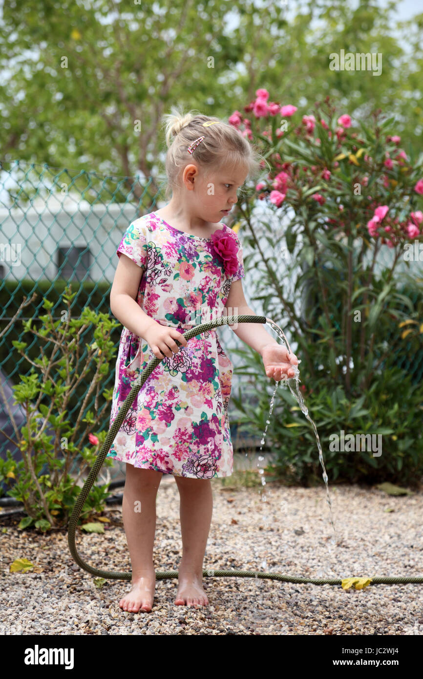 Little girl playing with water hose in the garden Stock Photo - Alamy