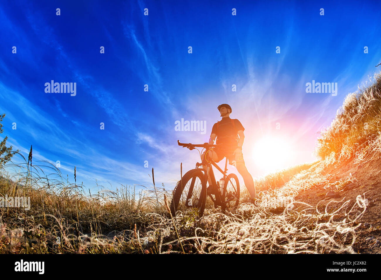 Low angle view of cyclist standing with mountain bike on trail at ...