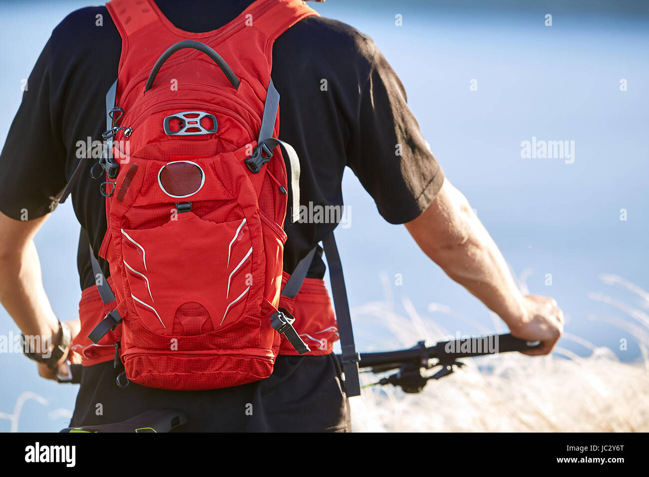 Rear view and close-up of the cyclist standing with mountain bike ...