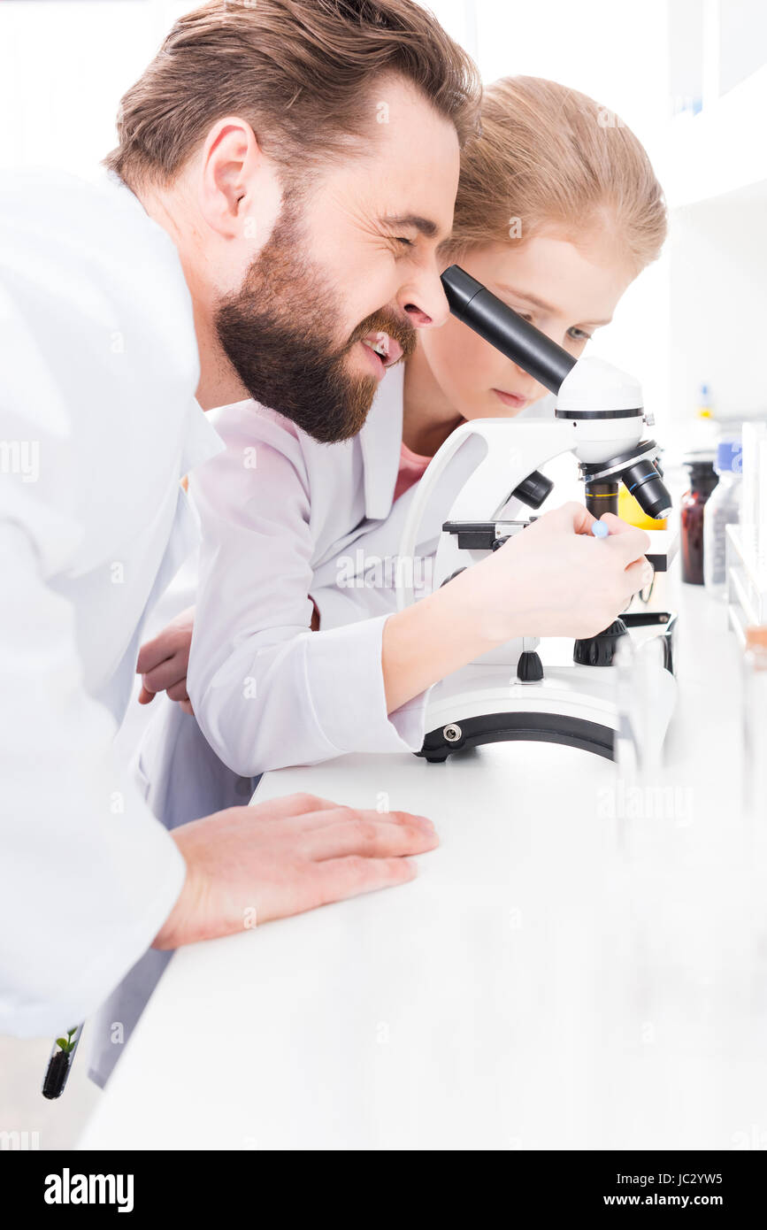 Teacher and student scientists working with microscope in laboratory ...