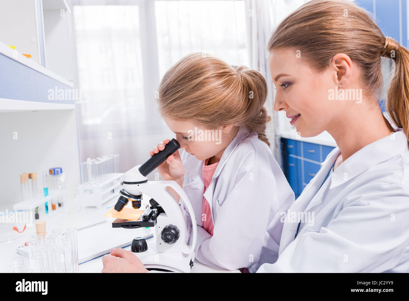Smiling teacher and student scientists working with microscope in ...