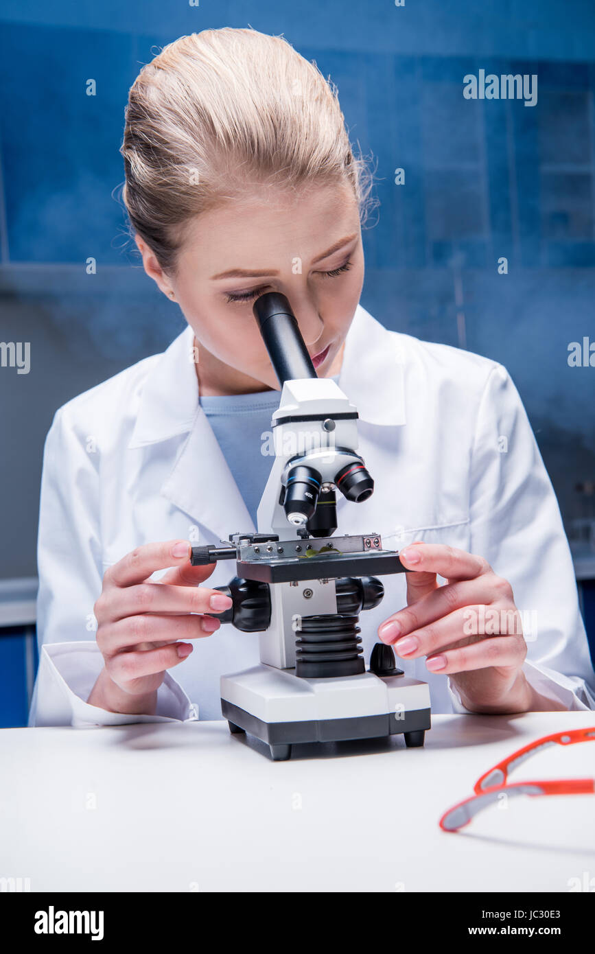 concentrated attractive blonde scientist working with microscope in ...