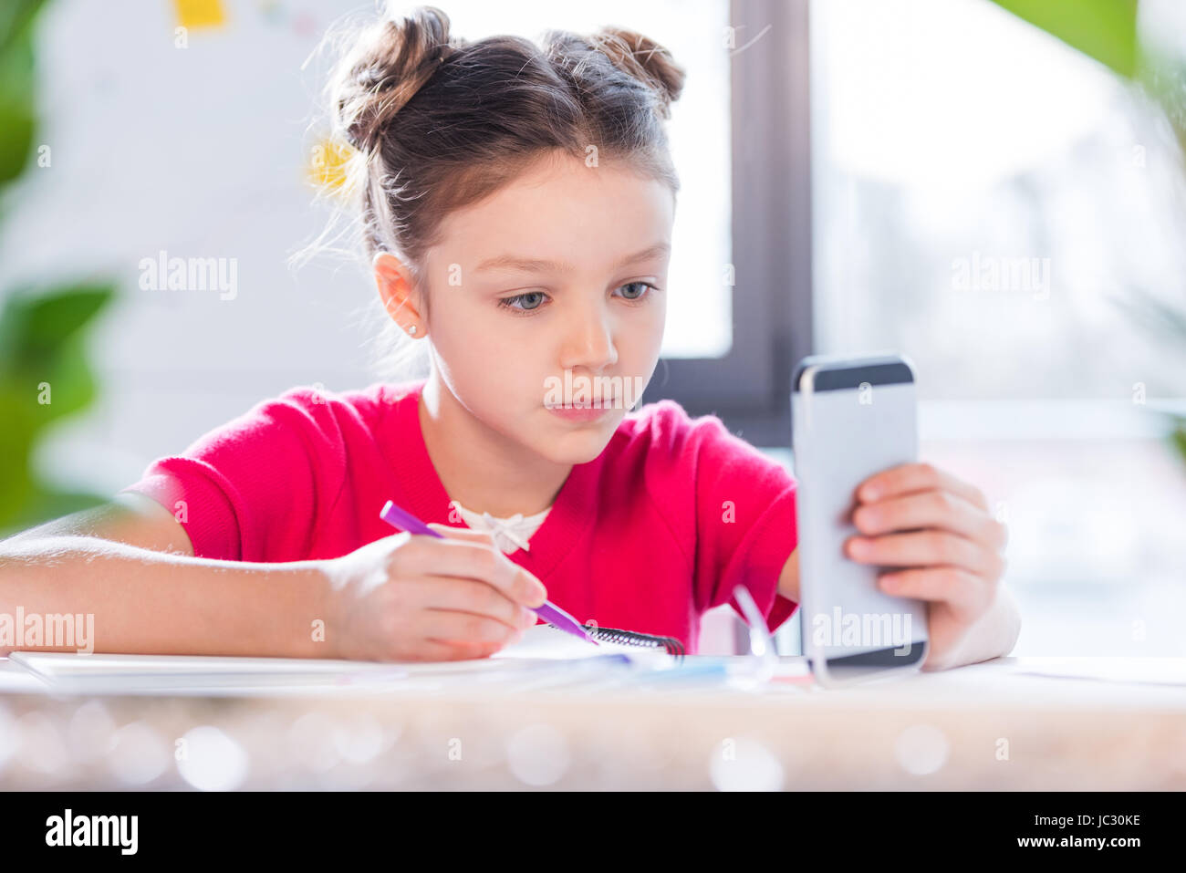 Adorable little girl drawing with pen and using smartphone Stock Photo ...