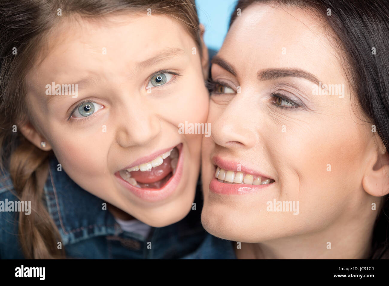 portrait of happy mother and daughter hugging in studio on blue Stock Photo - Alamy