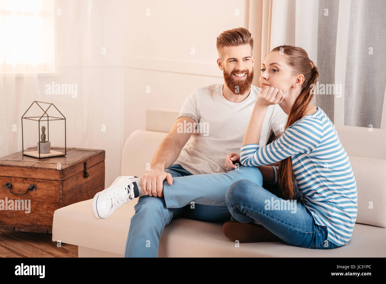 Beautiful happy young couple sitting together on sofa at home Stock ...