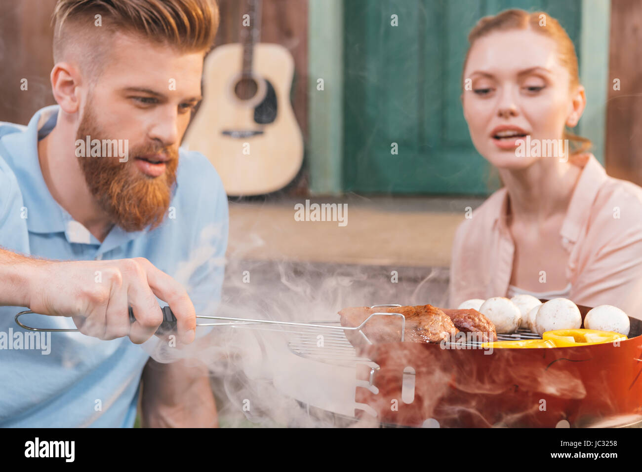 man and woman roasting meat and vegetables on barbecue grill Stock ...
